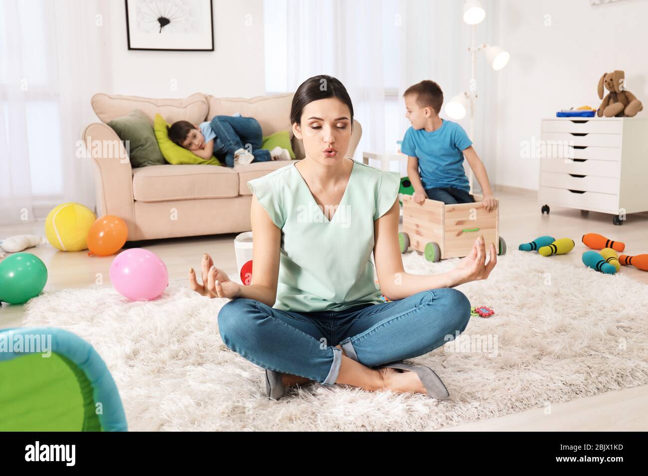 Young nanny meditating and trying to calm down while little boys are ...