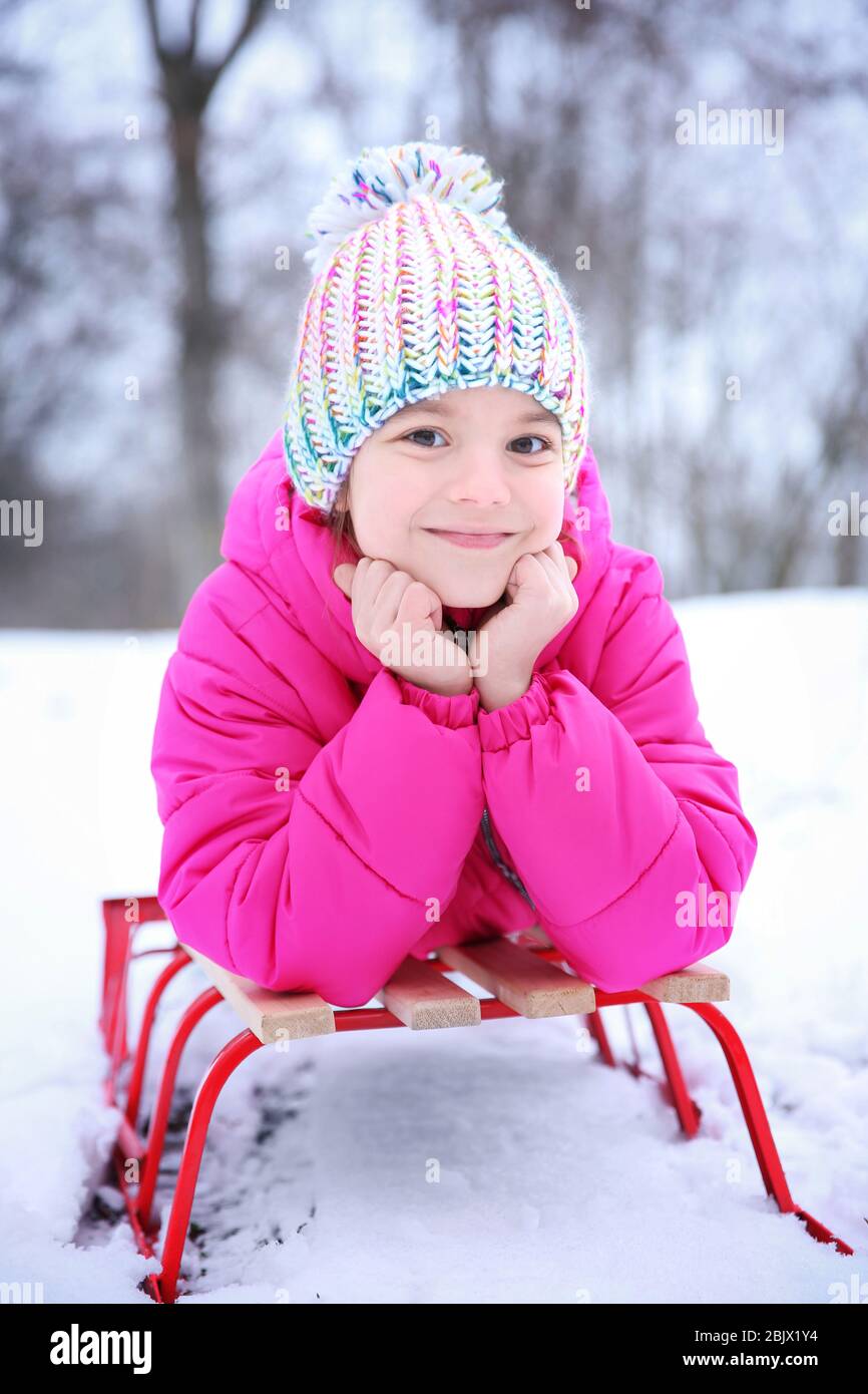 Cute girl with sled in snowy park on winter vacation Stock Photo - Alamy