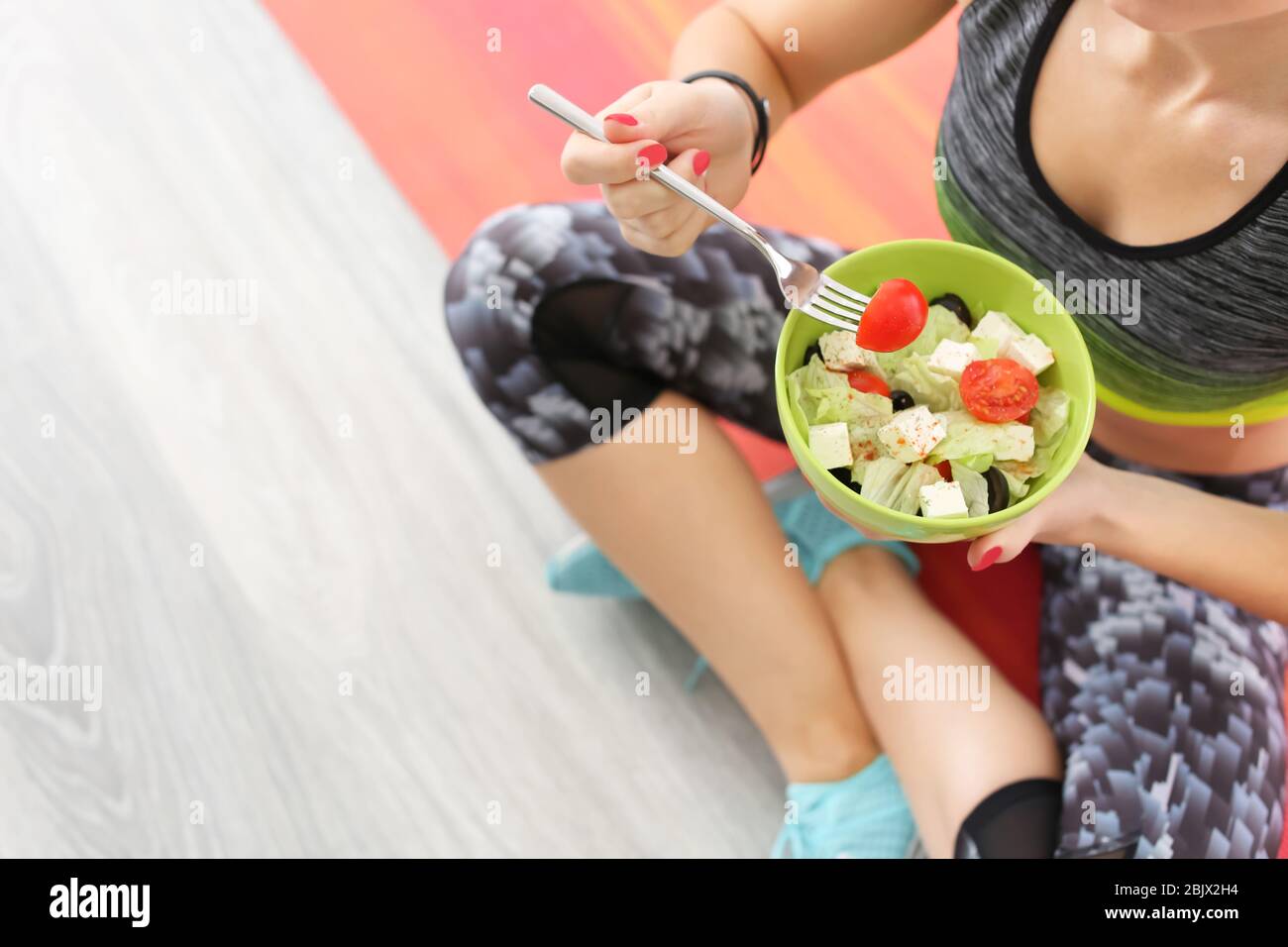 Sporty young woman eating salad after fitness training at home Stock ...