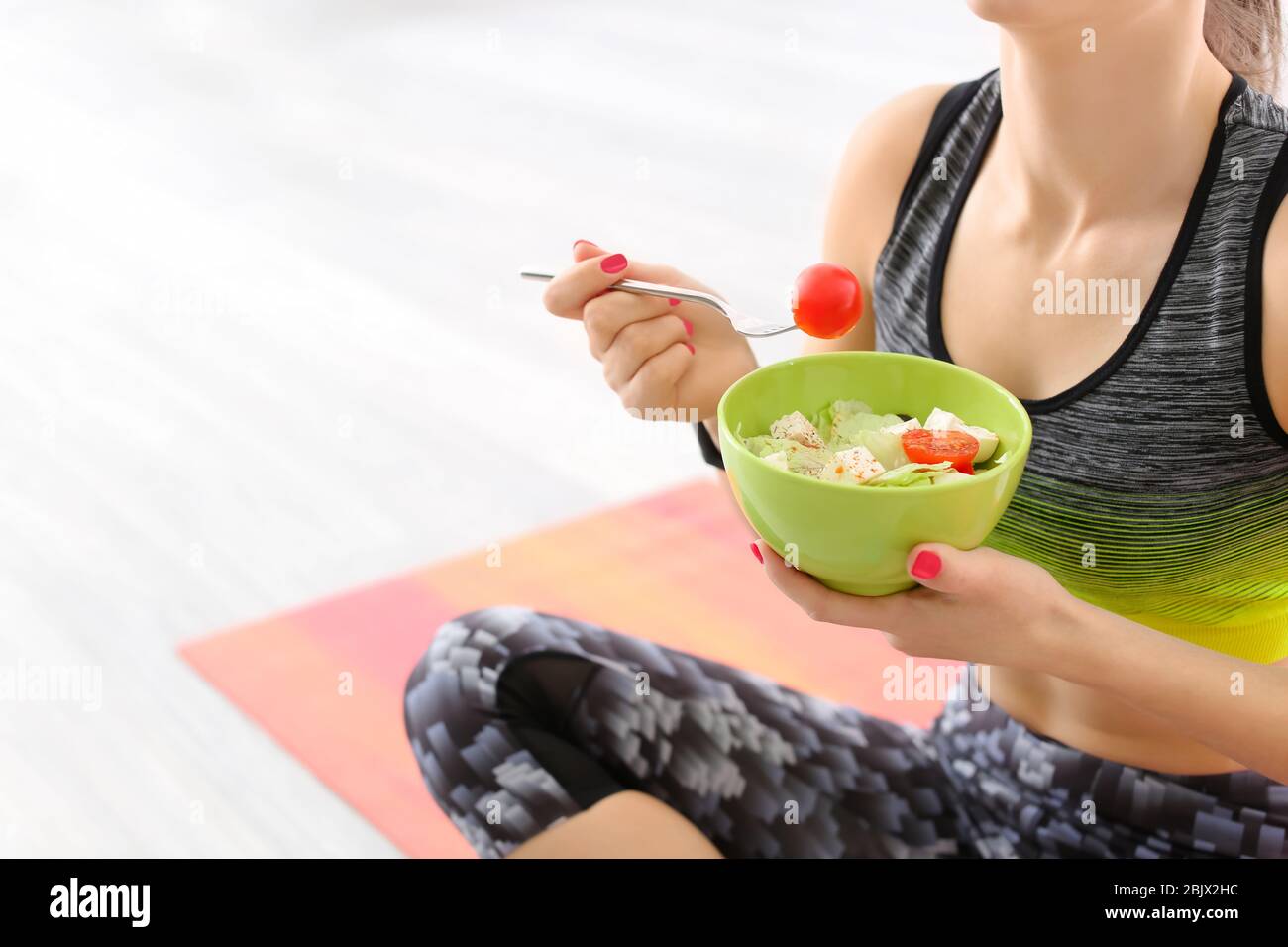 Sporty young woman eating salad after fitness training at home Stock ...