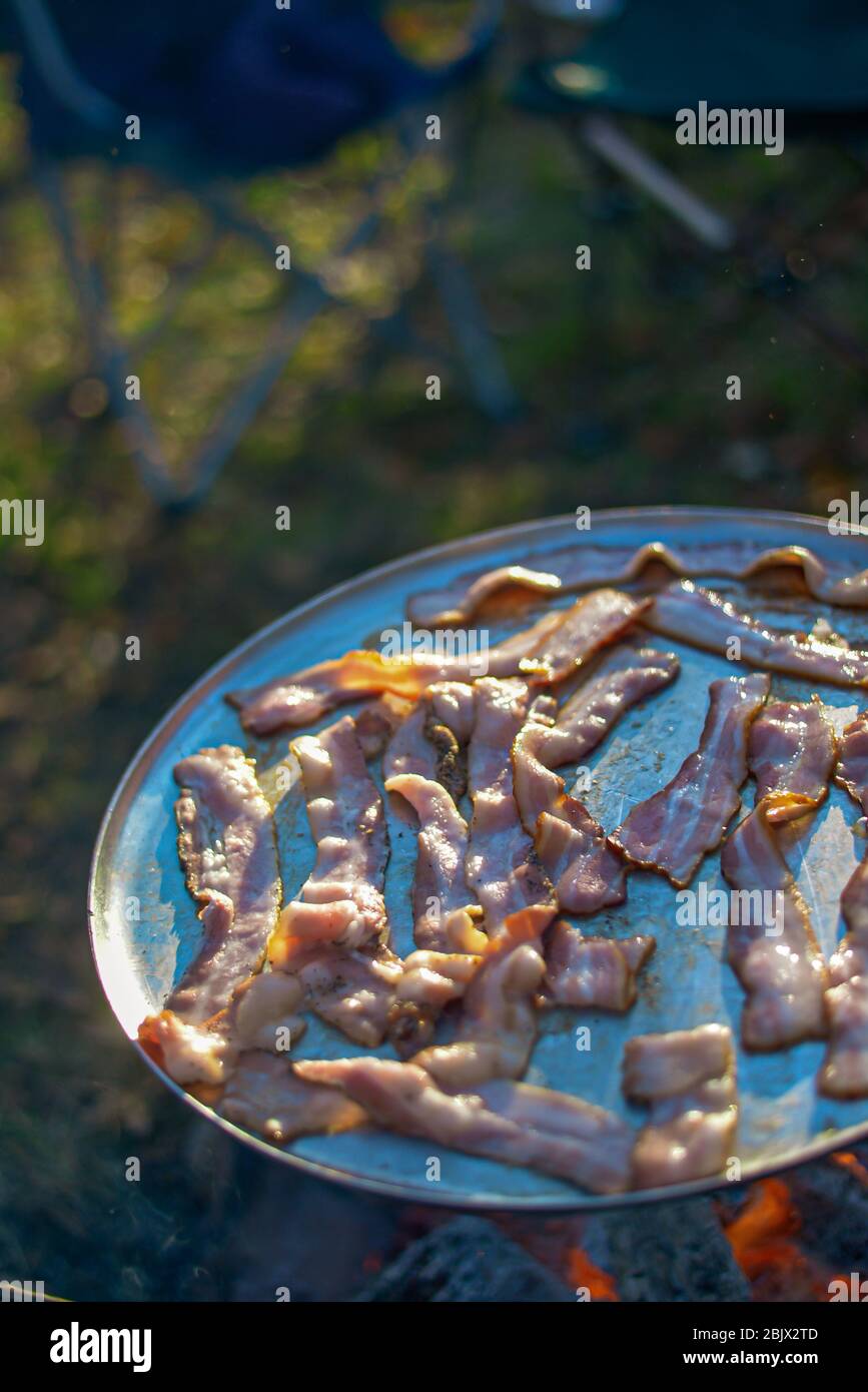 Cooking bacon over a recreational campfire outside Stock Photo - Alamy