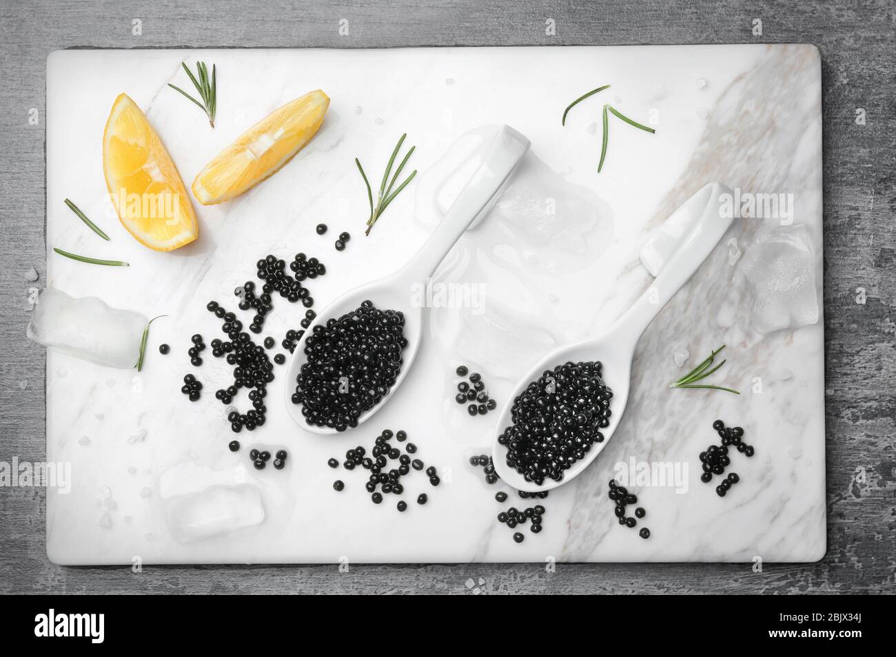 Spoons with delicious black caviar on marble board Stock Photo - Alamy