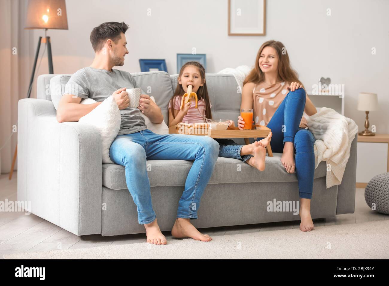 Happy family having breakfast on sofa at home Stock Photo - Alamy