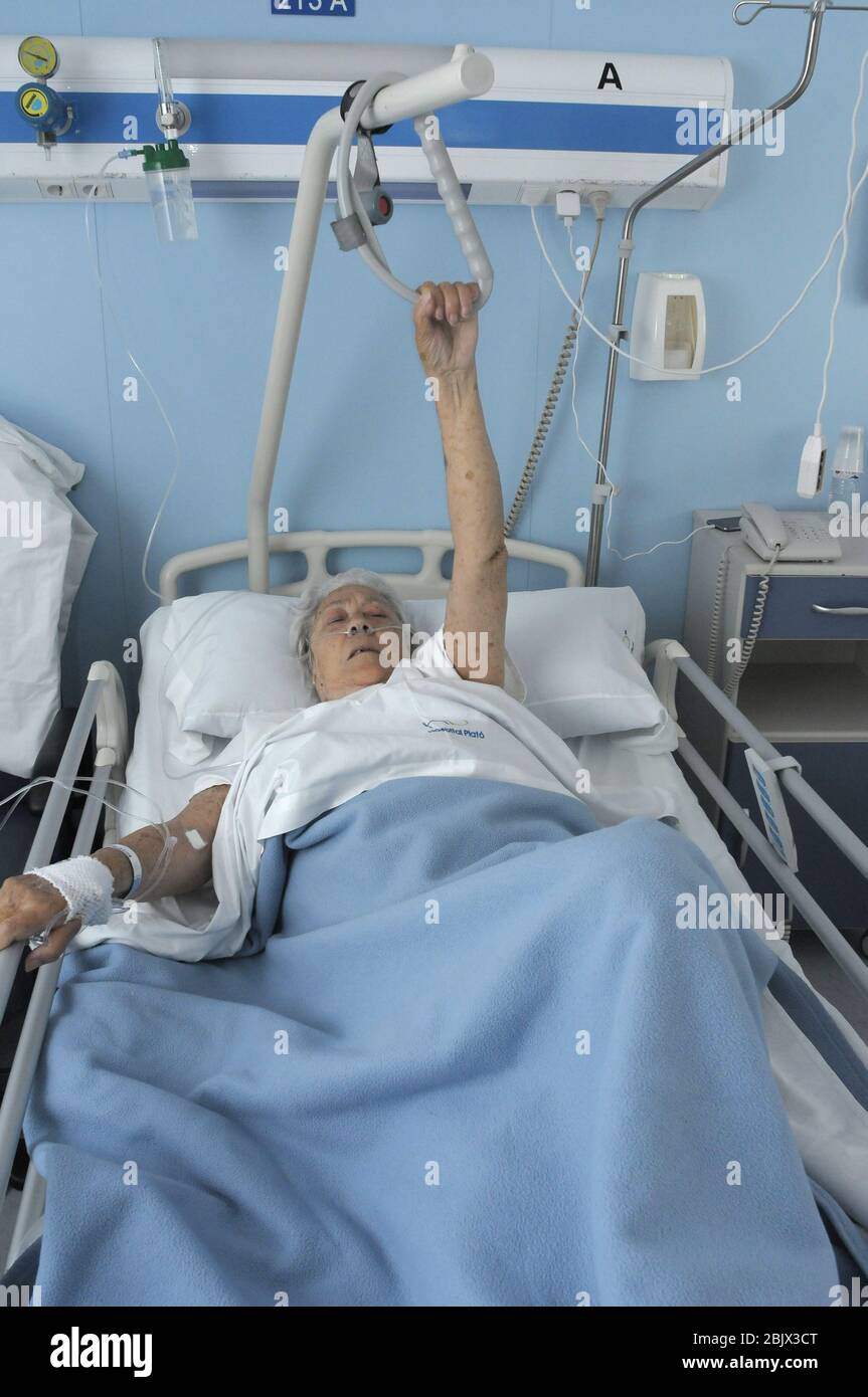 woman stretched out in a hospital bed, connected with different routes ...