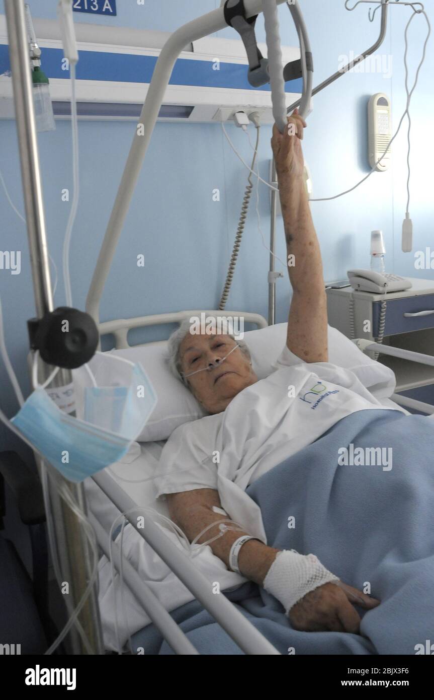 woman stretched out in a hospital bed, connected with different routes ...