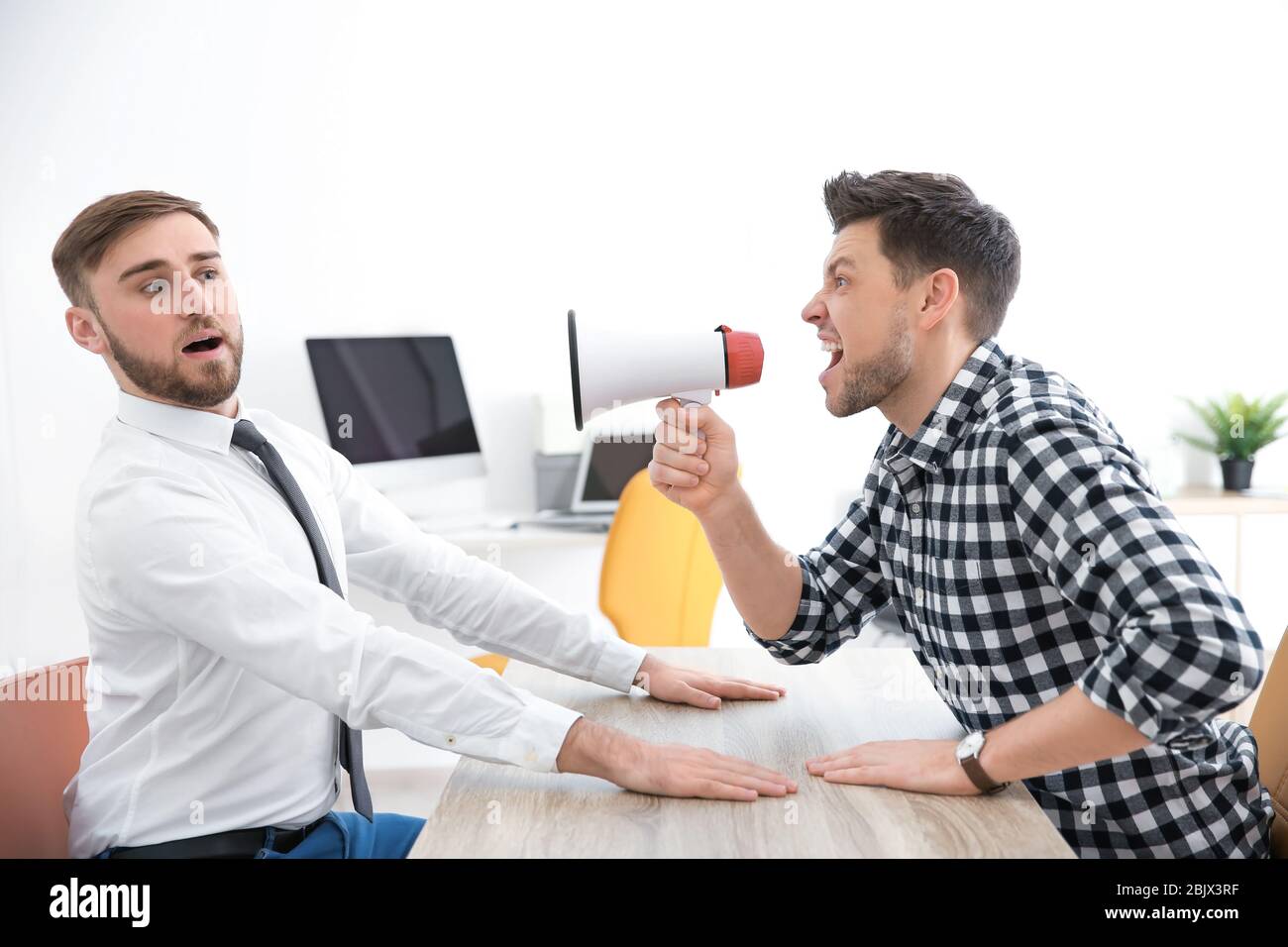 Angry boss with megaphone screaming at employee in office Stock Photo ...