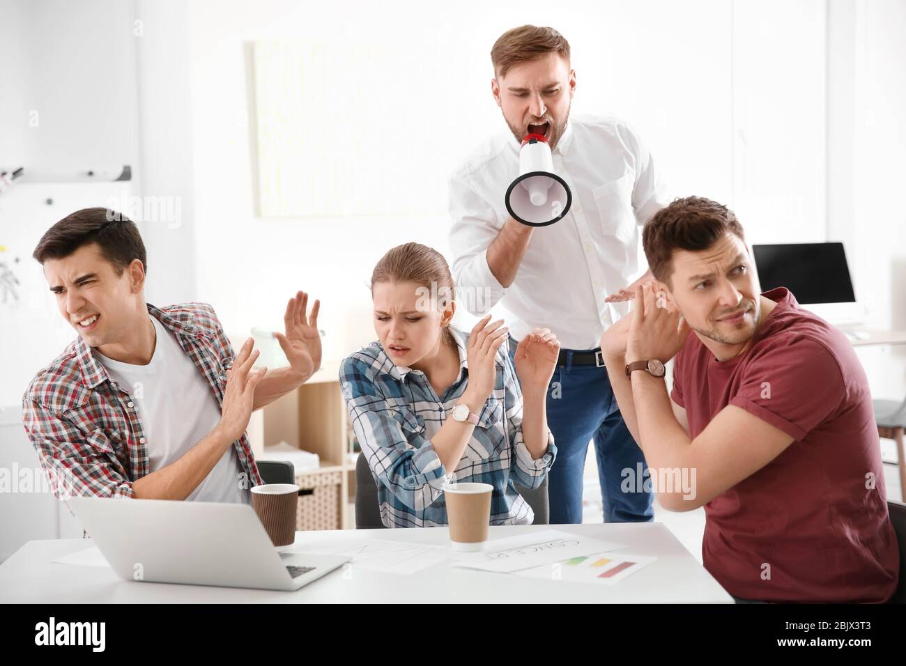 Angry boss with megaphone screaming at employees in office Stock Photo ...