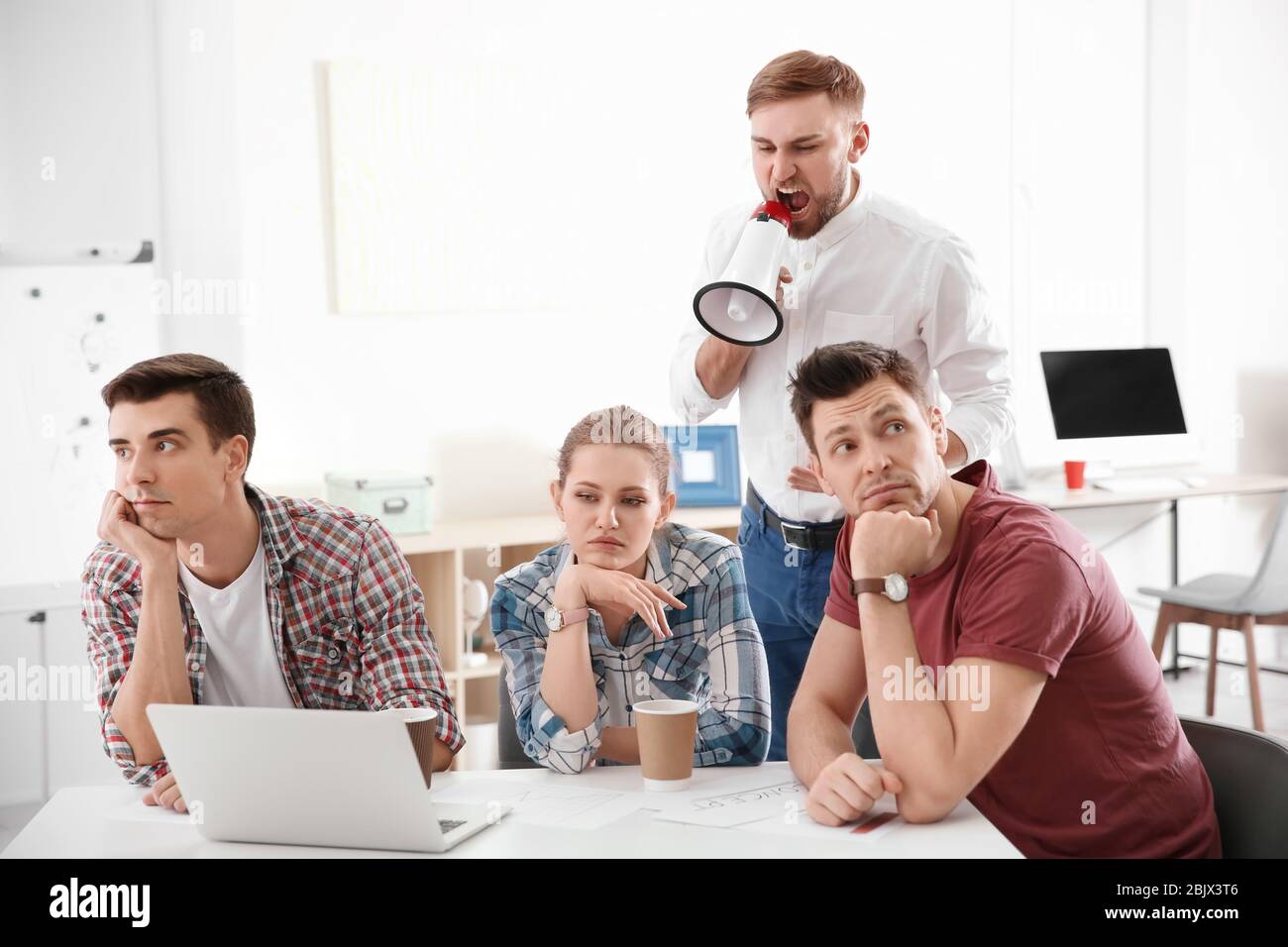 Angry boss with megaphone screaming at employees in office Stock Photo ...