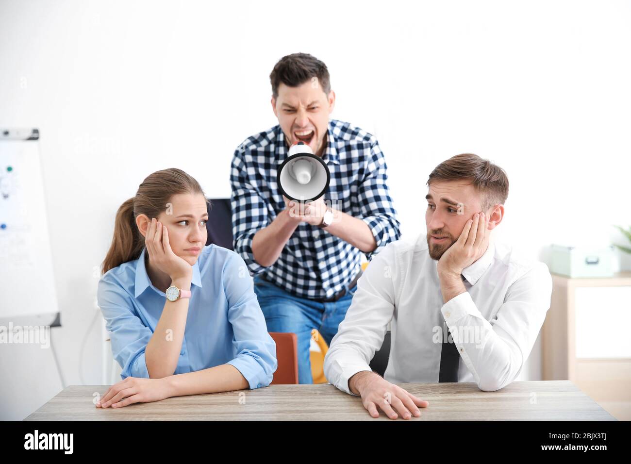 Angry boss with megaphone screaming at employees in office Stock Photo ...