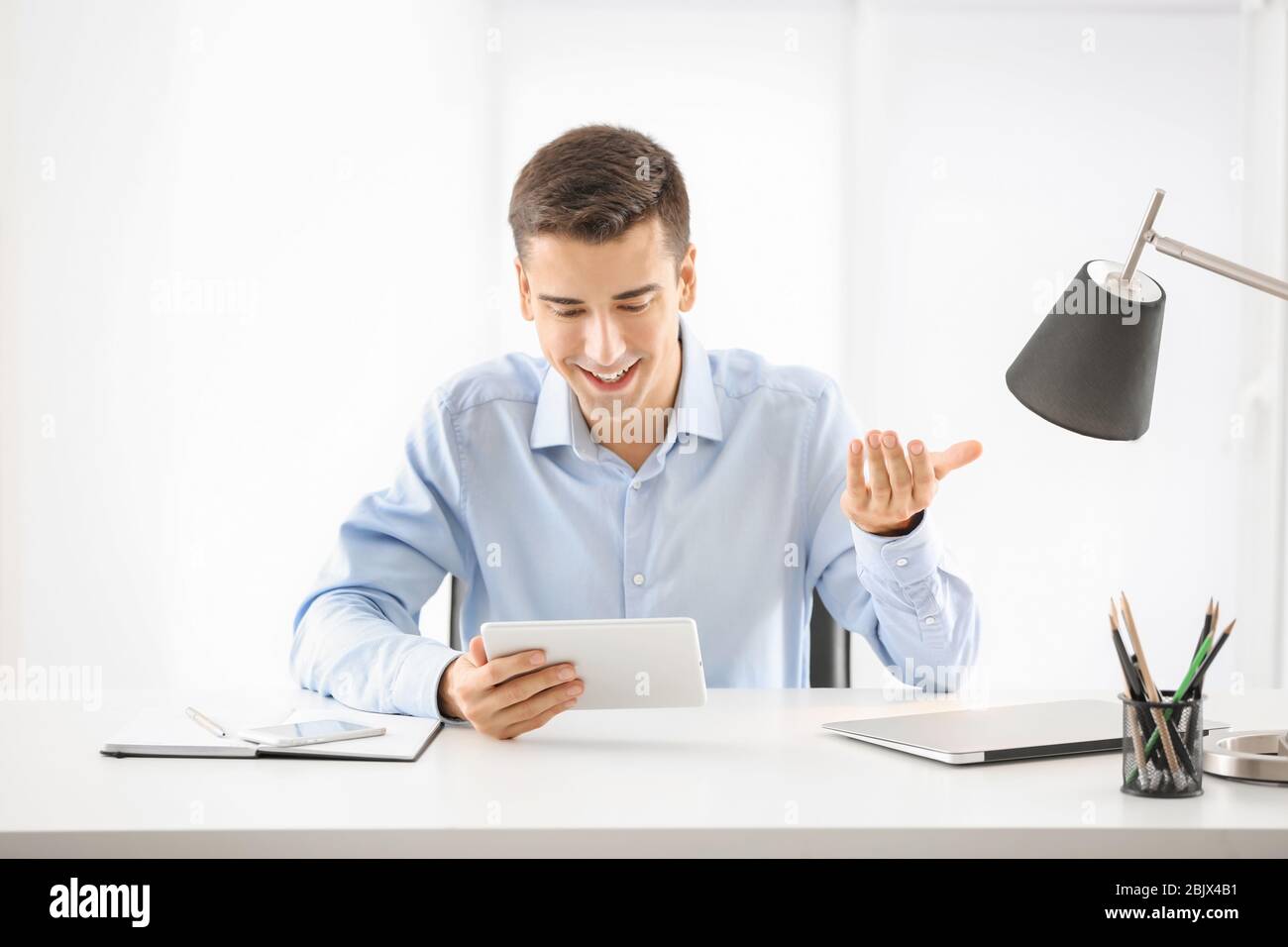 Young man using tablet computer at table indoors Stock Photo - Alamy