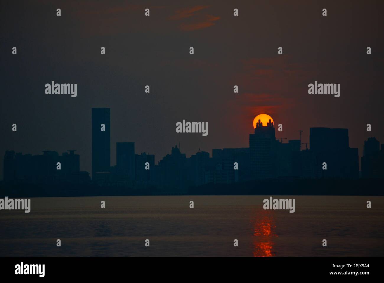 Wuhan: Sunset over the city skyline from the East Lake, with smog and a ...