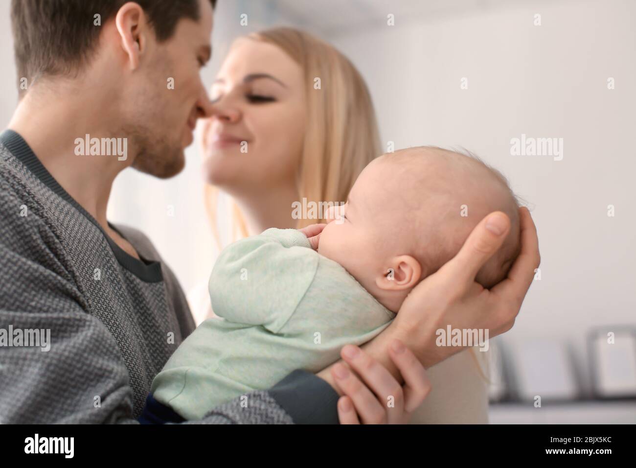 Young parents with sleeping baby at home Stock Photo - Alamy