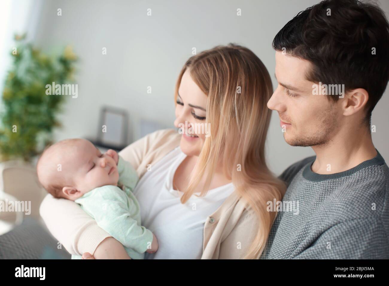 Young parents with sleeping baby at home Stock Photo - Alamy