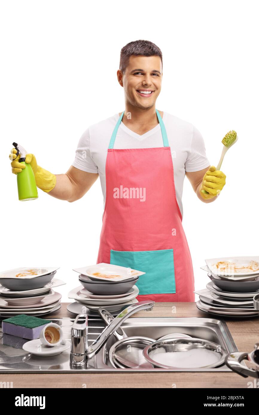 Smiling young man with a pile of dirty plates holding a brush and a ...