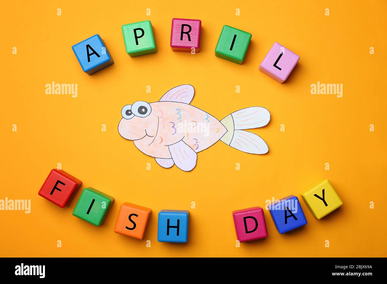 Paper fish and cubes on color background. April fool's day celebration ...