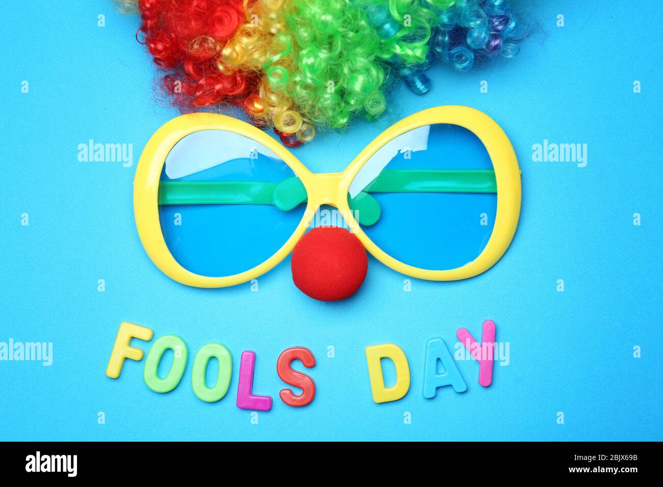 Big glasses, clown nose and rainbow wig on color background. April fool ...