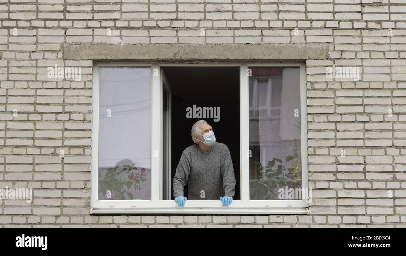 Old man stay at window in protection mask. Isolated at home on ...