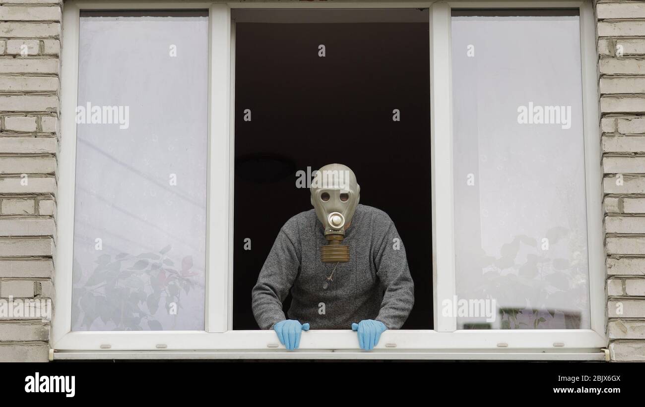 Old man stay at window in gas mask. Isolated at home on quarantine ...