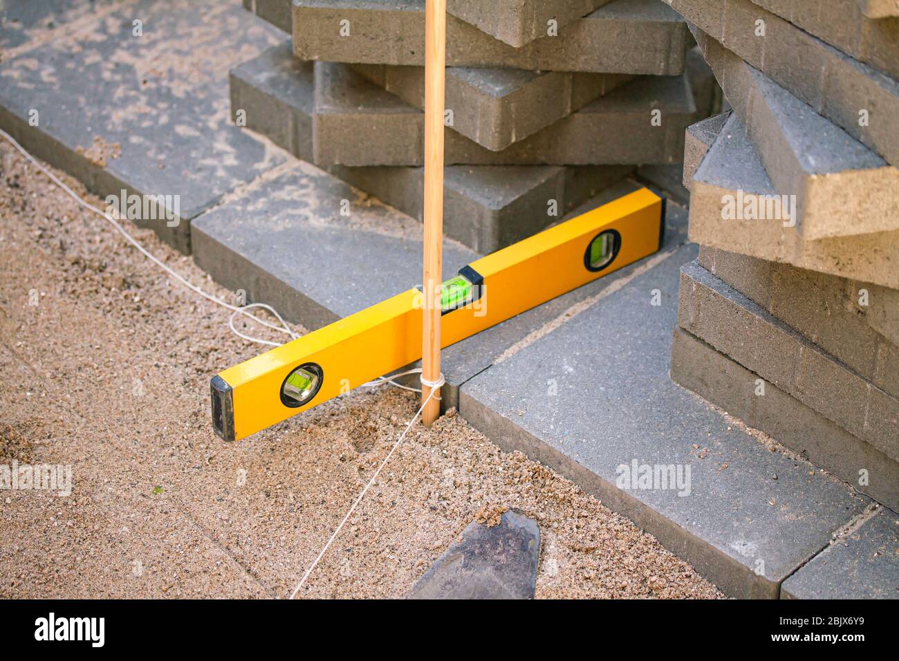 Close up of spirit level placed on outdoor pavers or tiles with ...