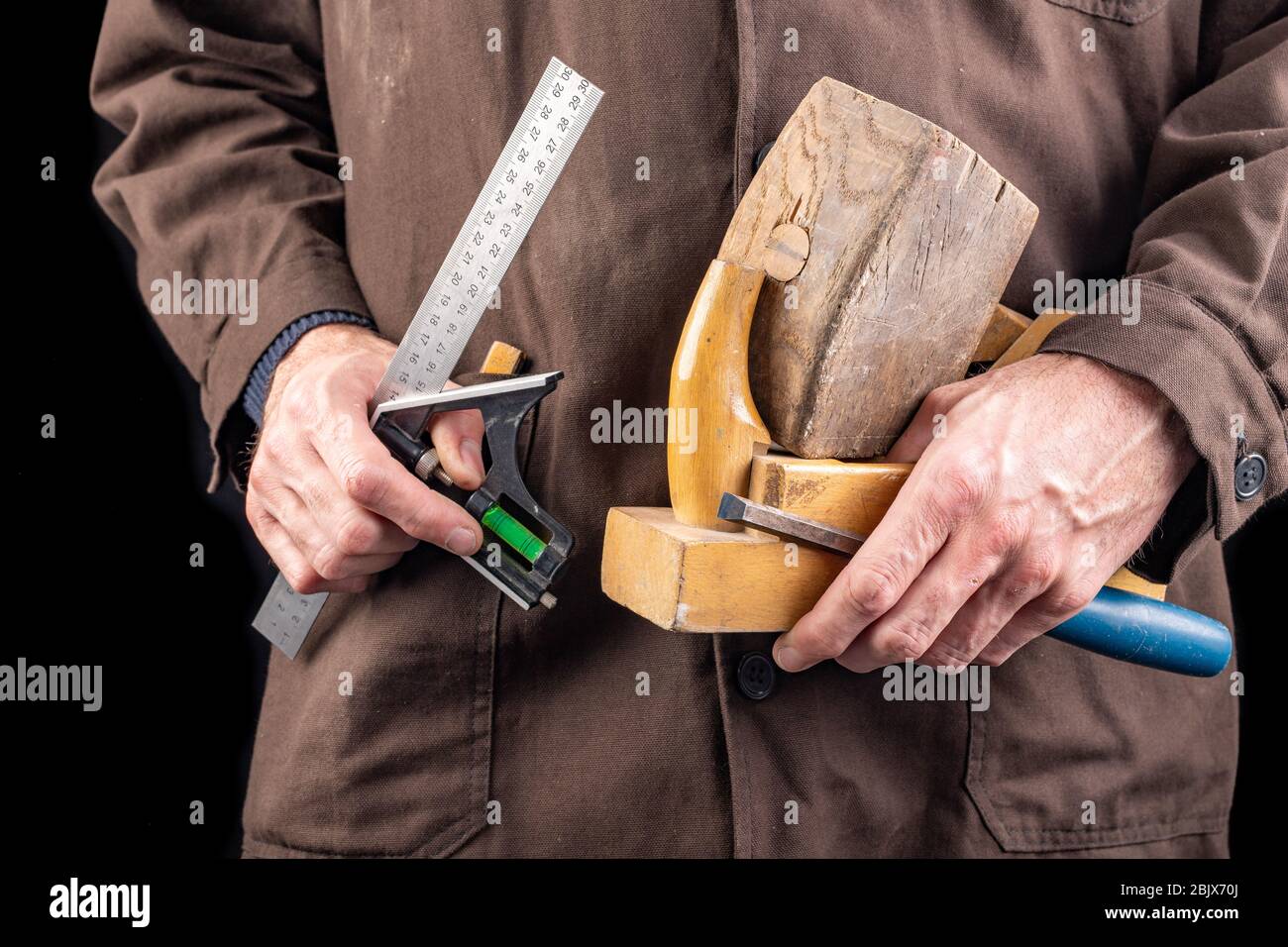 A carpenter with a planer and a hammer in his hand. Worker in a ...