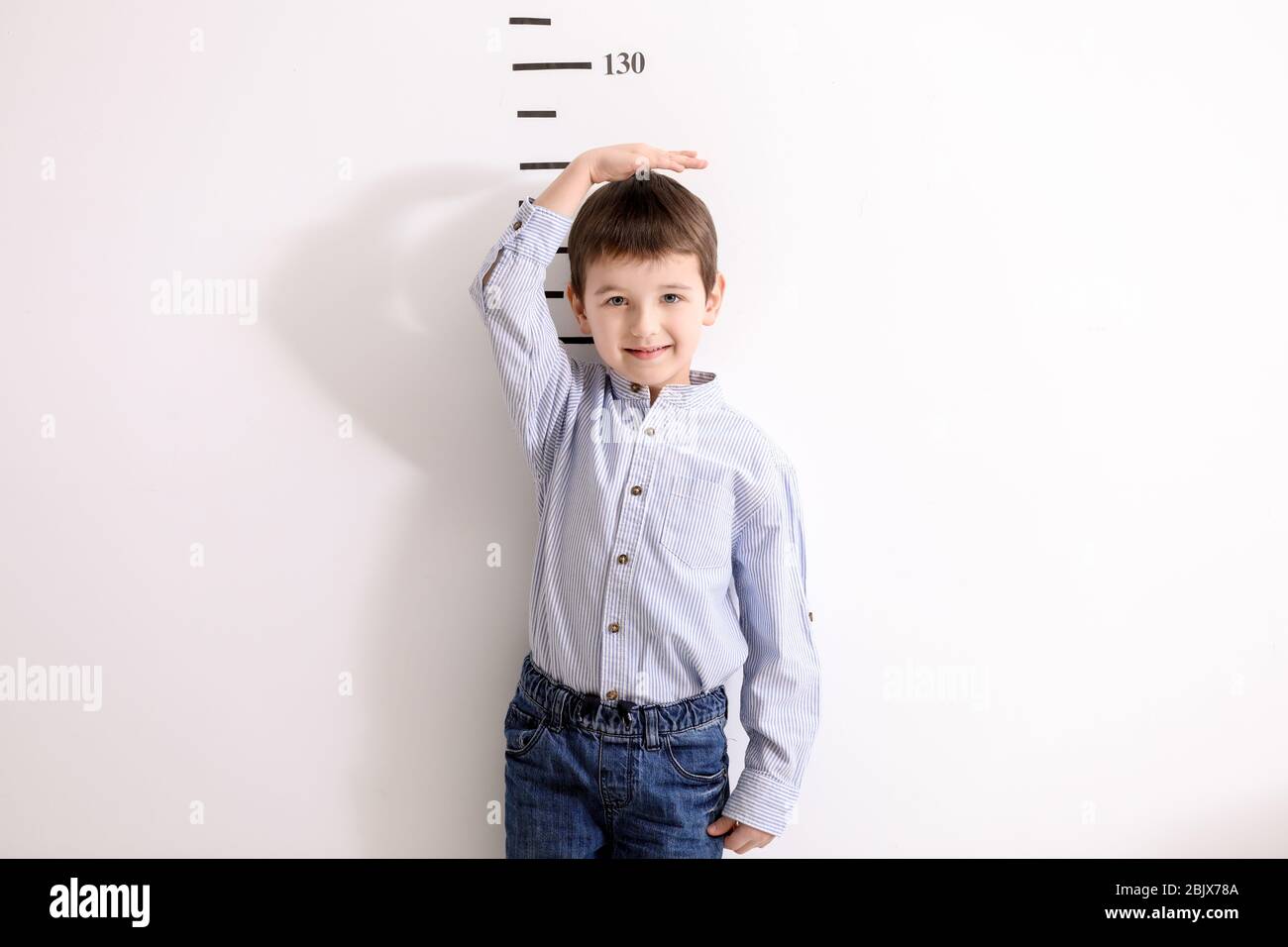 Little boy measuring height near white wall Stock Photo - Alamy