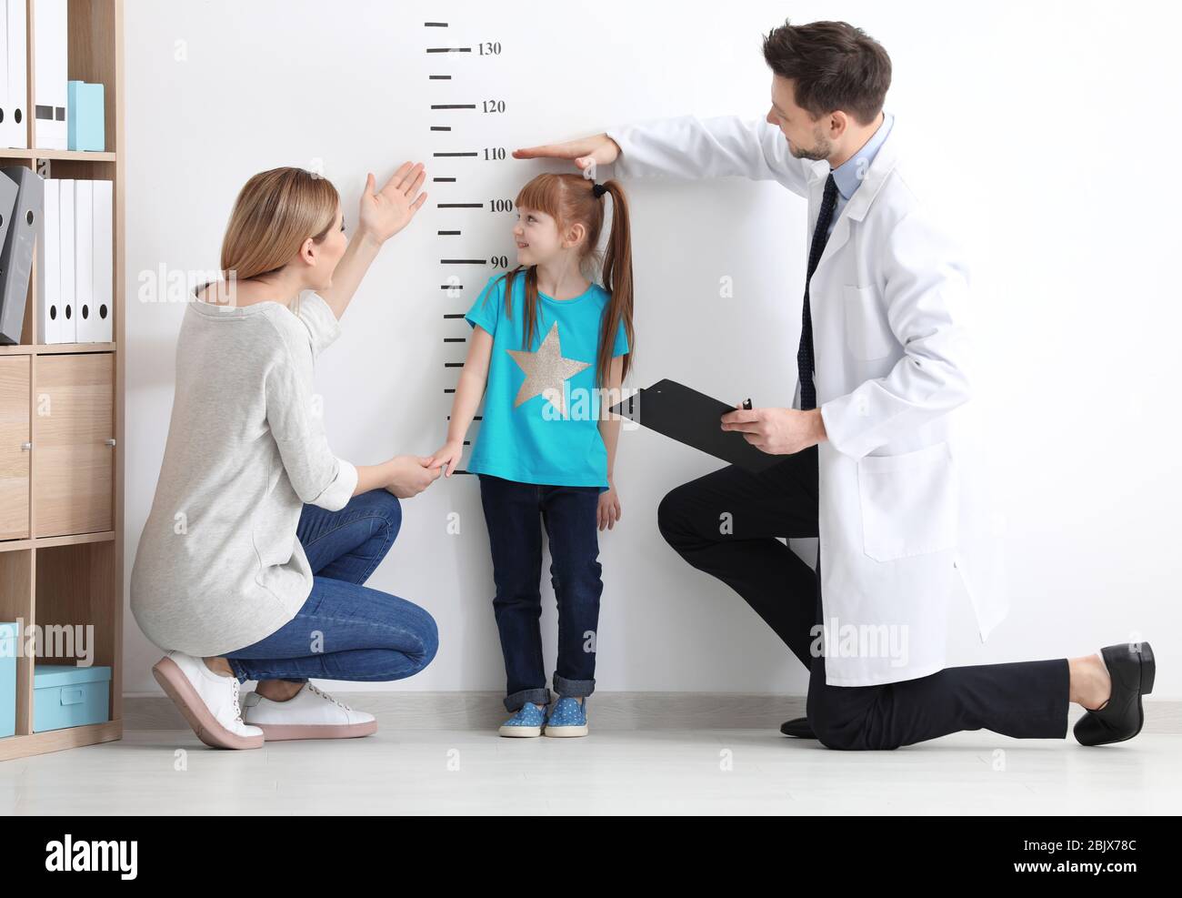 Male doctor measuring height of little girl in clinic Stock Photo - Alamy