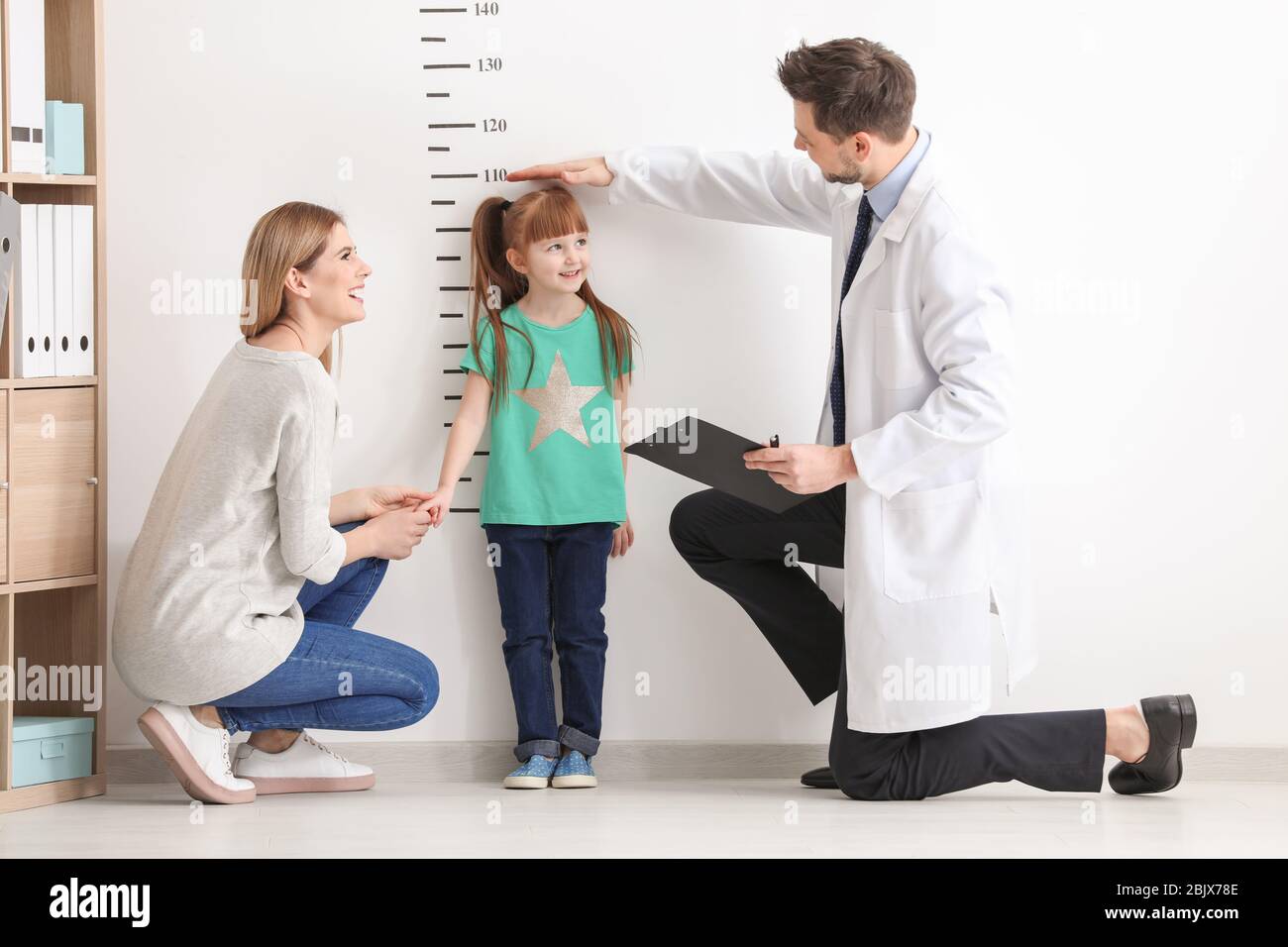 Male doctor measuring height of little girl in clinic Stock Photo - Alamy