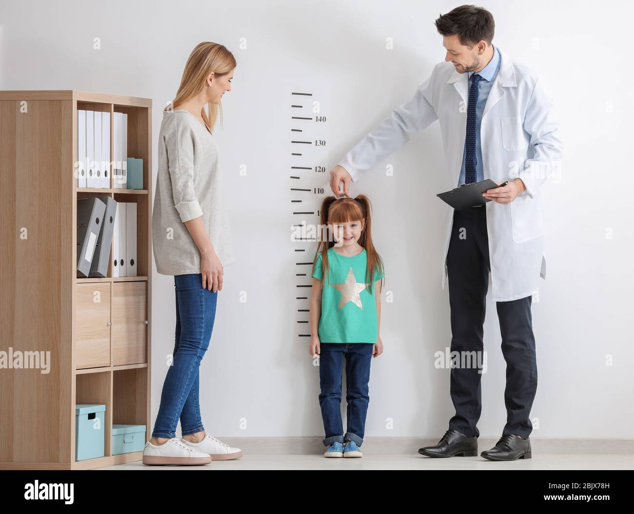Male doctor measuring height of little girl in clinic Stock Photo - Alamy