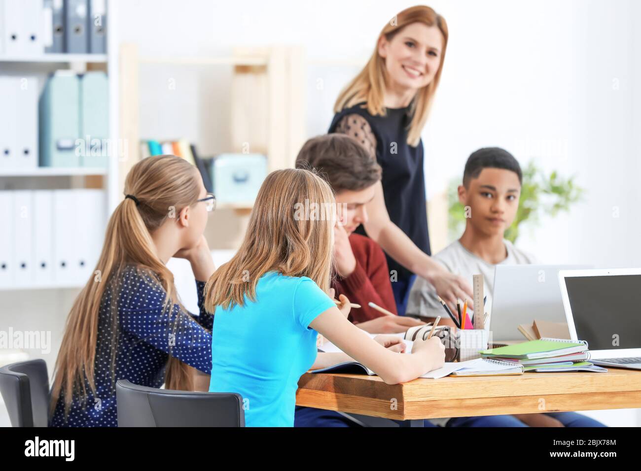 Group of teenagers doing homework with teacher in classroom Stock Photo ...