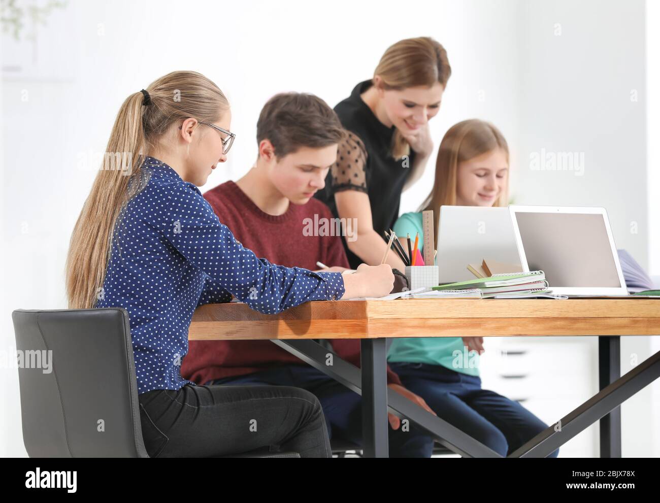Group of teenagers doing homework with teacher in classroom Stock Photo ...