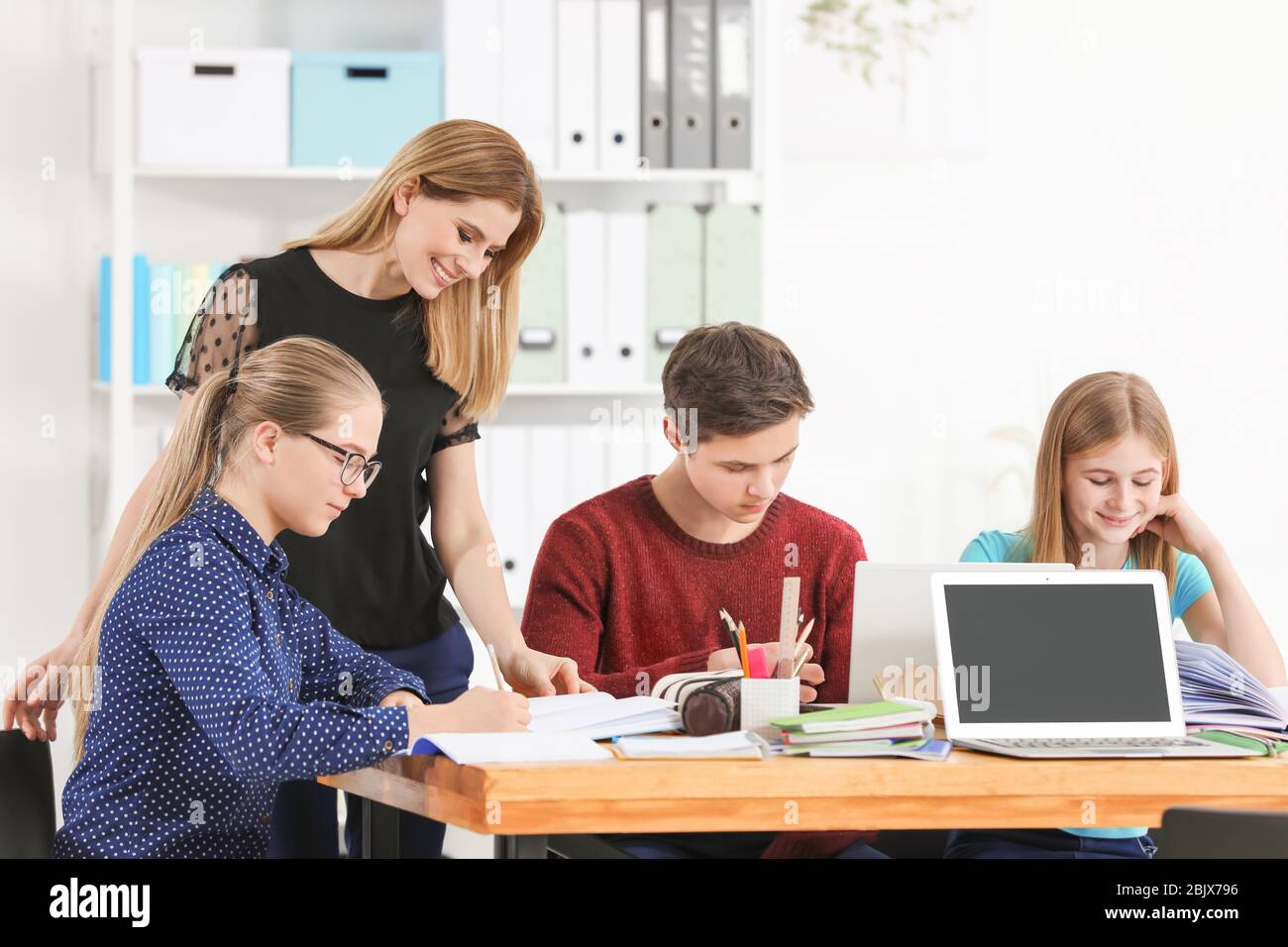 Group of teenagers doing homework with teacher in classroom Stock Photo ...