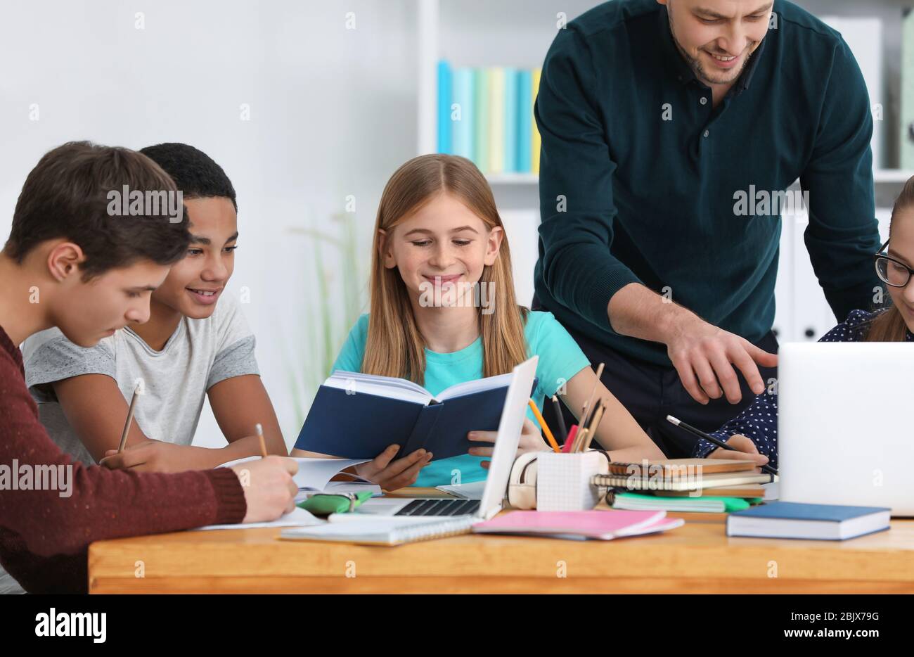 Group of teenagers doing homework with teacher in classroom Stock Photo ...