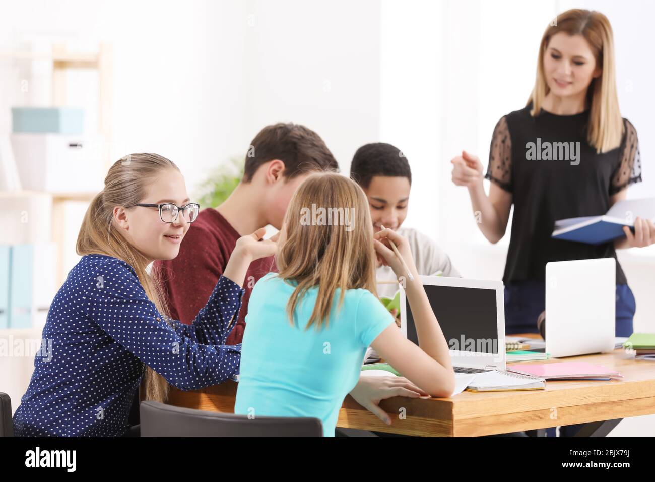 Group of teenagers doing homework with teacher in classroom Stock Photo ...