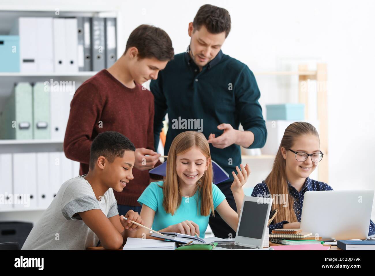 Group of teenagers doing homework with teacher in classroom Stock Photo ...
