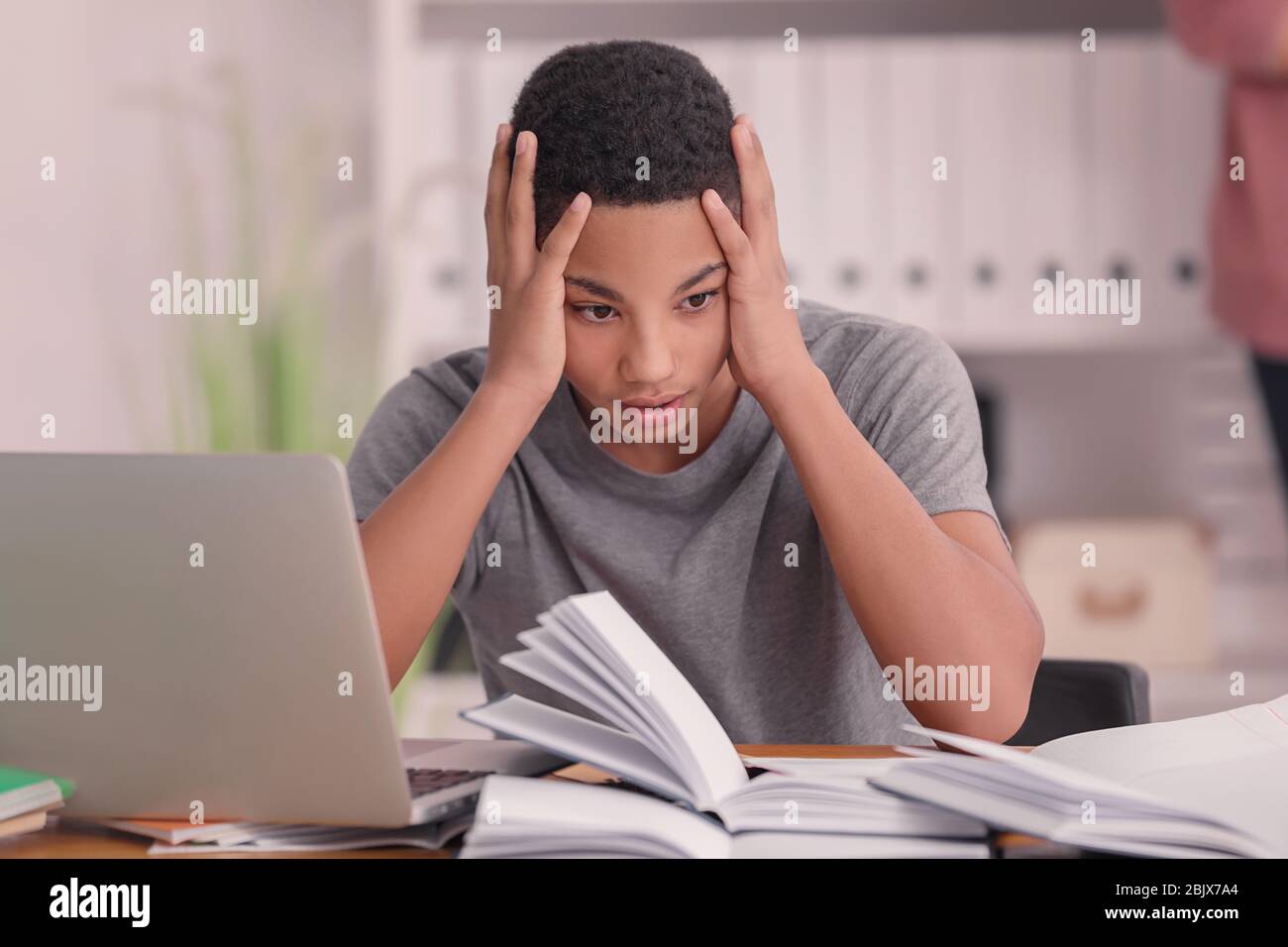 African American teenage boy doing homework at table Stock Photo - Alamy