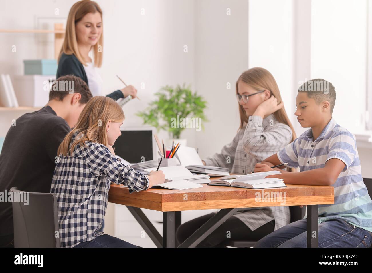 Group of teenagers doing homework with teacher in classroom Stock Photo ...