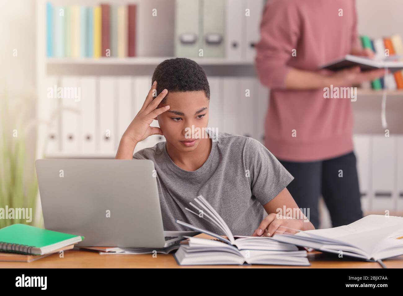 African American teenage boy doing homework at table Stock Photo - Alamy