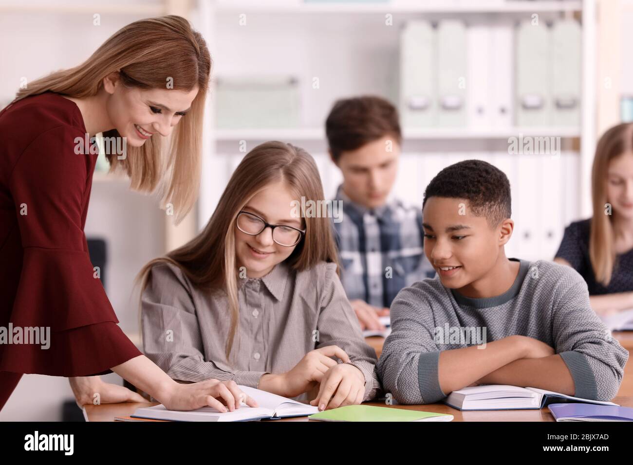 Group of teenagers doing homework with teacher in classroom Stock Photo ...