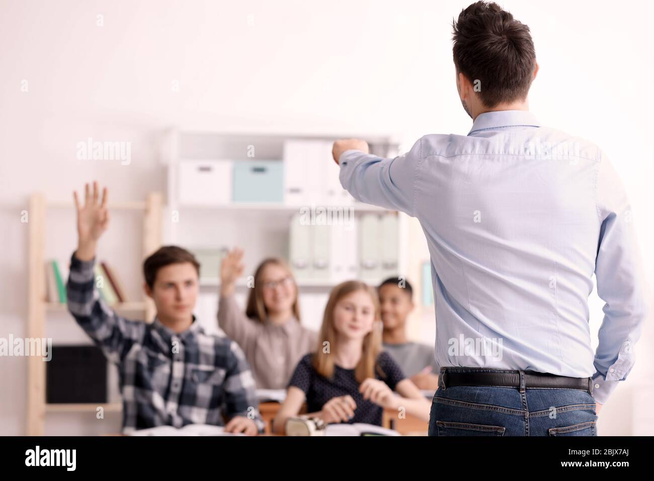 Group of teenagers doing homework with teacher in classroom Stock Photo ...