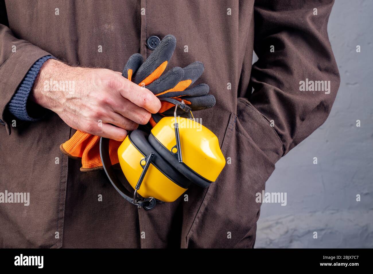 Production worker with gloves and hearing protectors in hand. A ...