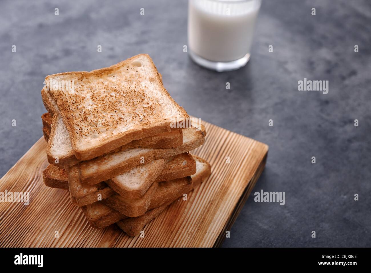 Wooden board with toasted bread on table Stock Photo - Alamy