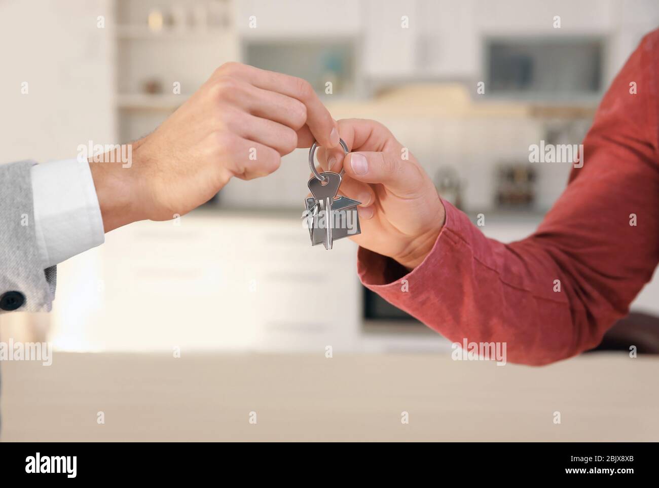 Real estate agent giving house key to young man indoors Stock Photo - Alamy