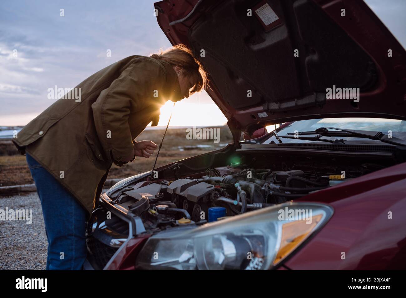 Woman Looking under Car Hood Sun Flare Stock Photo - Alamy