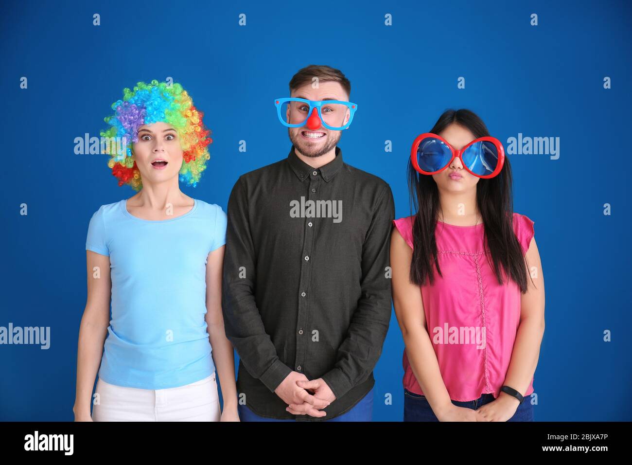 Young people in funny disguise posing on color background. April fool's ...
