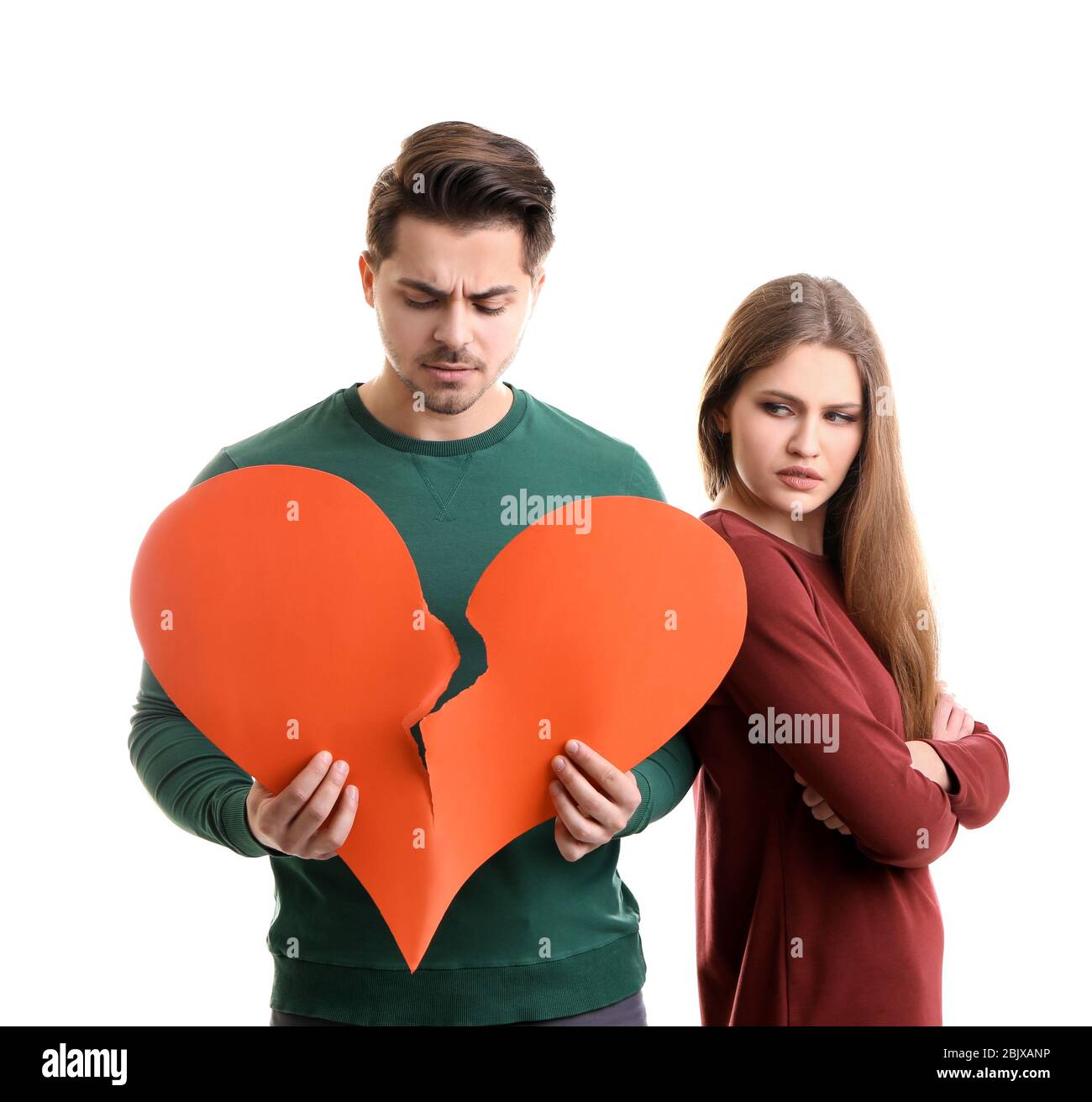 Young man tearing paper heart near his girlfriend on white background ...