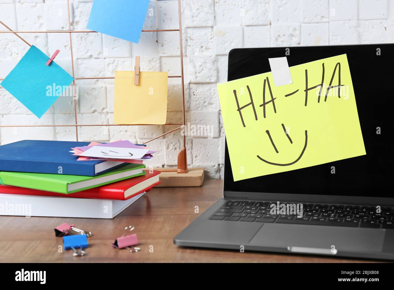 Laptop with "Ha-ha" card on office table. April fool's day celebration ...