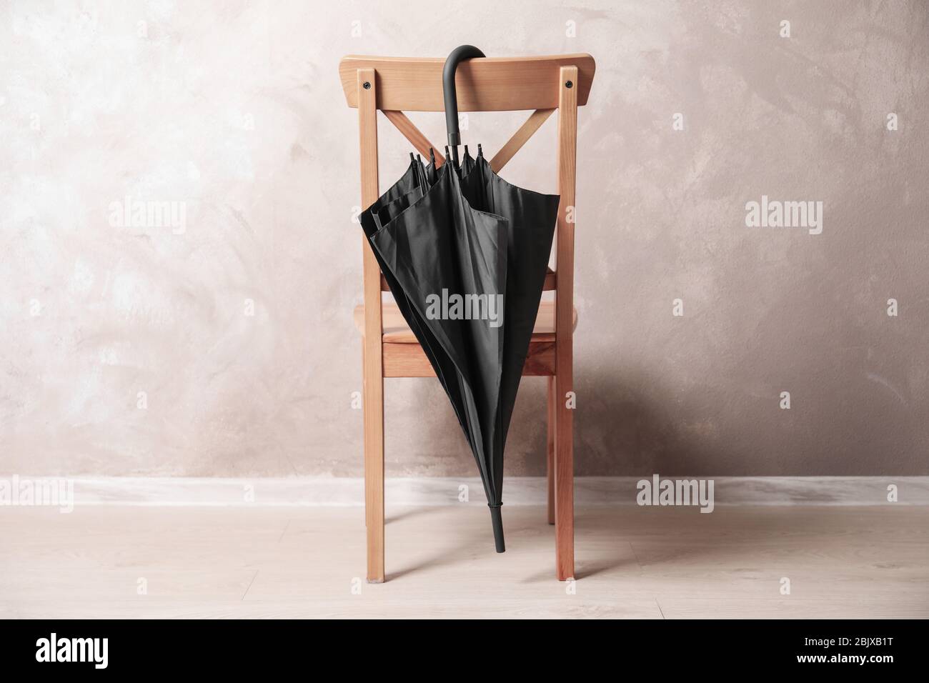 Black umbrella hanging on chair indoors Stock Photo - Alamy