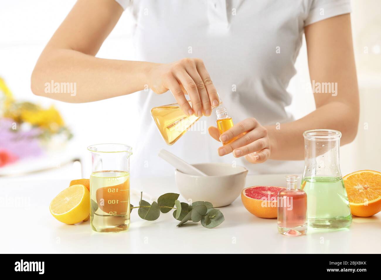 Woman pouring perfume oil into glass bottle at table Stock Photo - Alamy