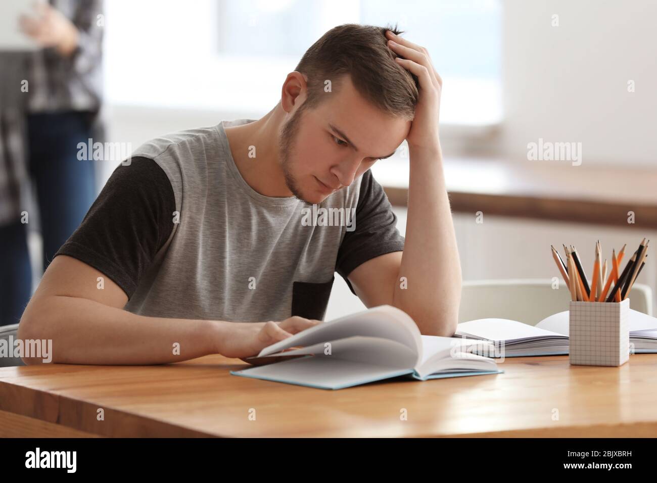 Male student doing homework in library Stock Photo - Alamy