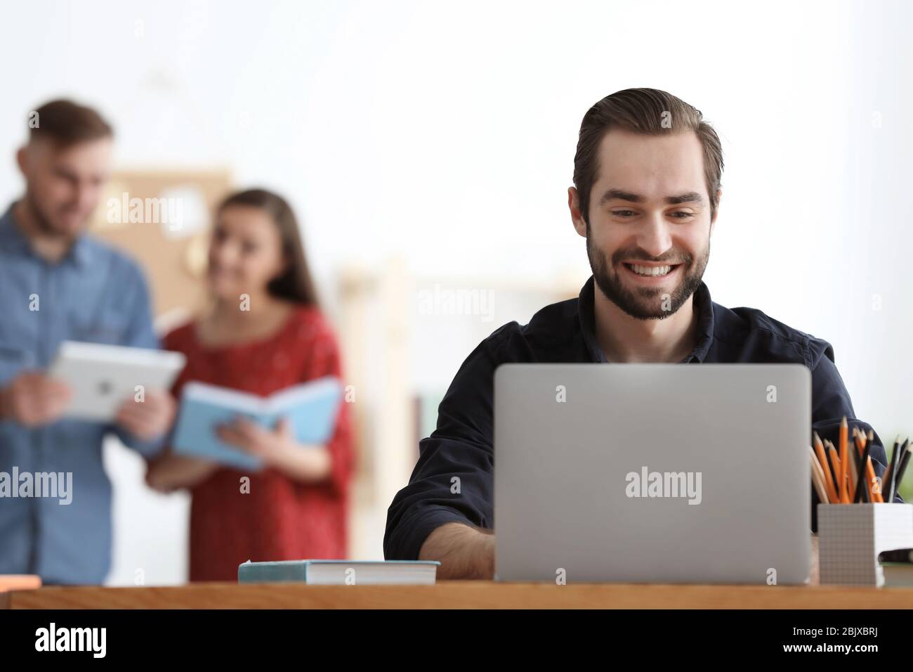 Male student with laptop doing homework in classroom Stock Photo - Alamy